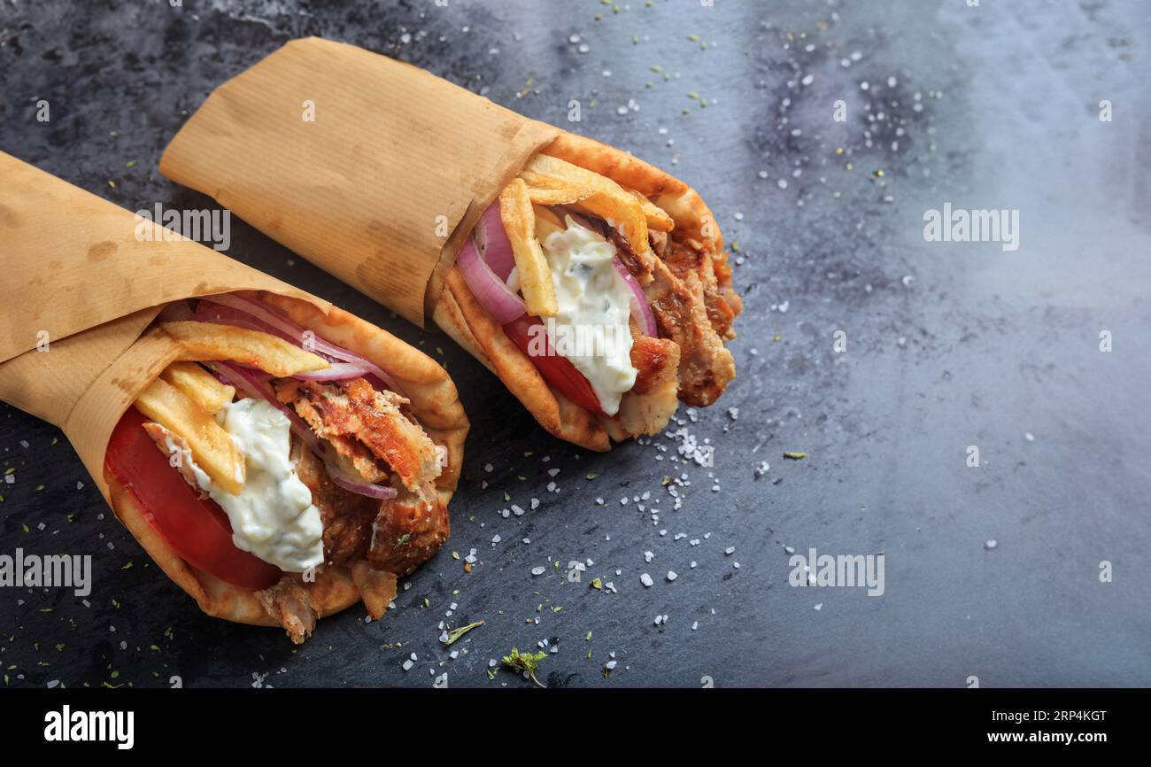 Greek gyros wrapped in pita bread on a black dish. Delicious food ...