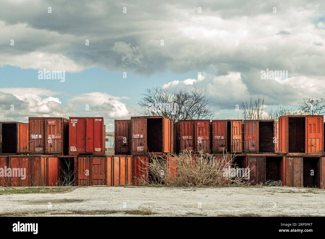 A long row of empty metal containers on a lot with sandy floors Stock ...