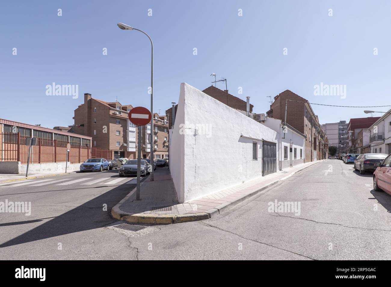 A white one-story urban building with a gray portal at a street ...