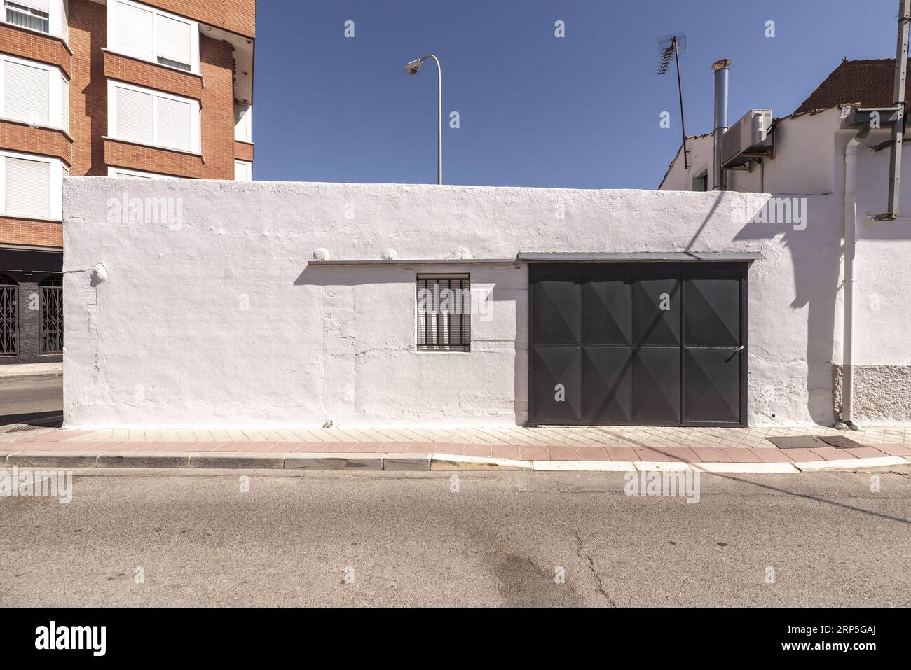 A white one-story urban building with a gray portal at a street ...