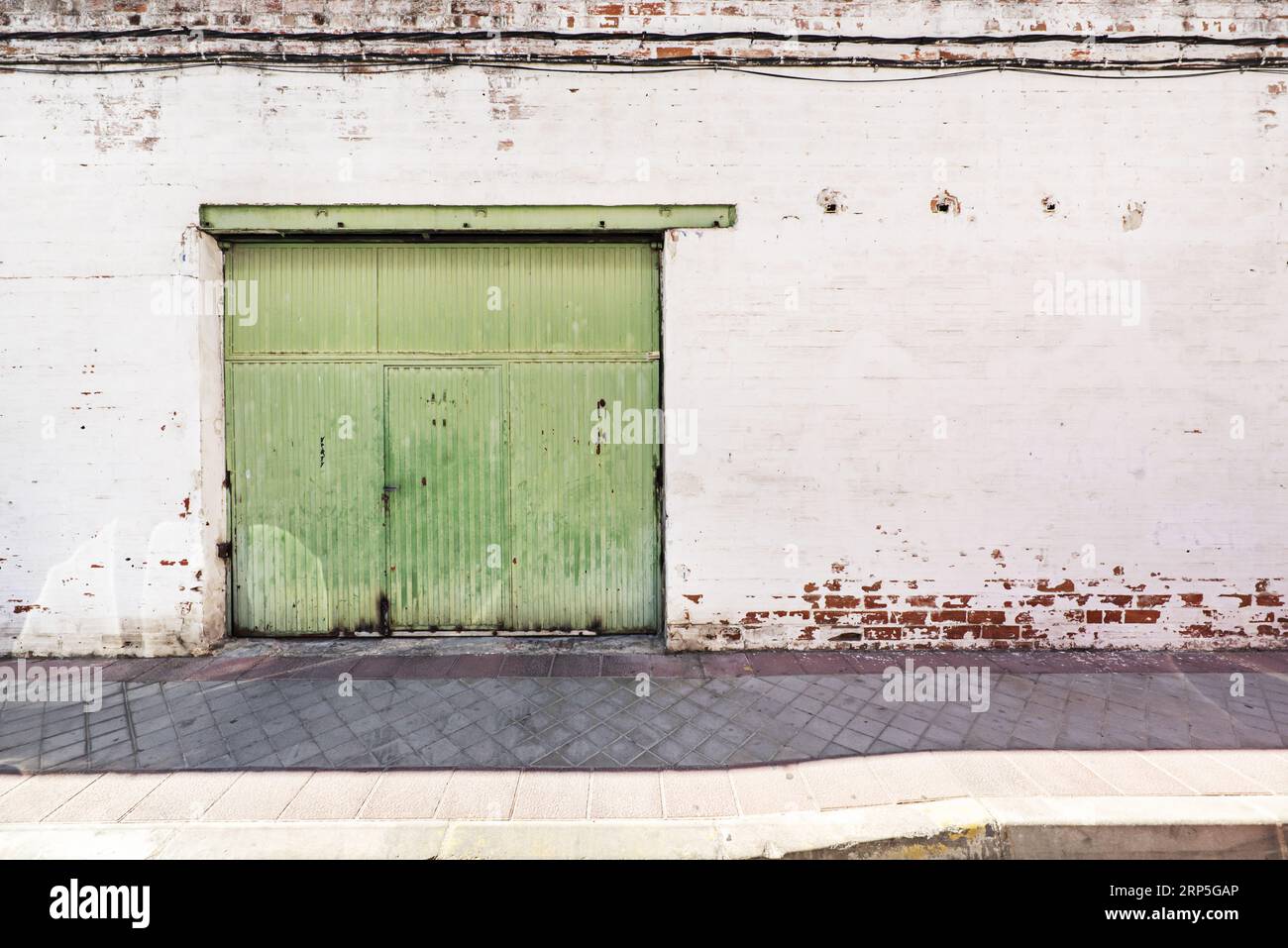 An old industrial warehouse one story high with a green metal portal ...