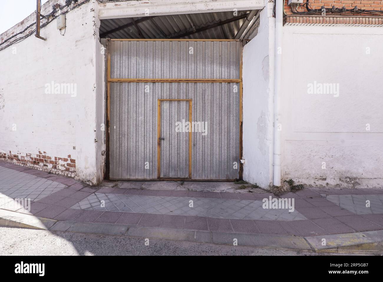 Metal access gate to a garage in an old warehouse made of white painted ...