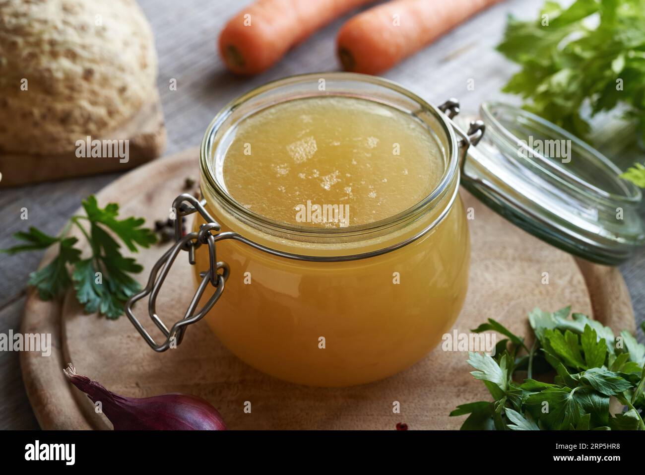 Chicken bone broth in a glass jar, with fresh vegetables in the ...