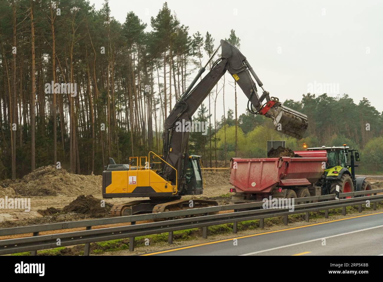 Repair work on the road. The excavator loads the earth into the tractor ...