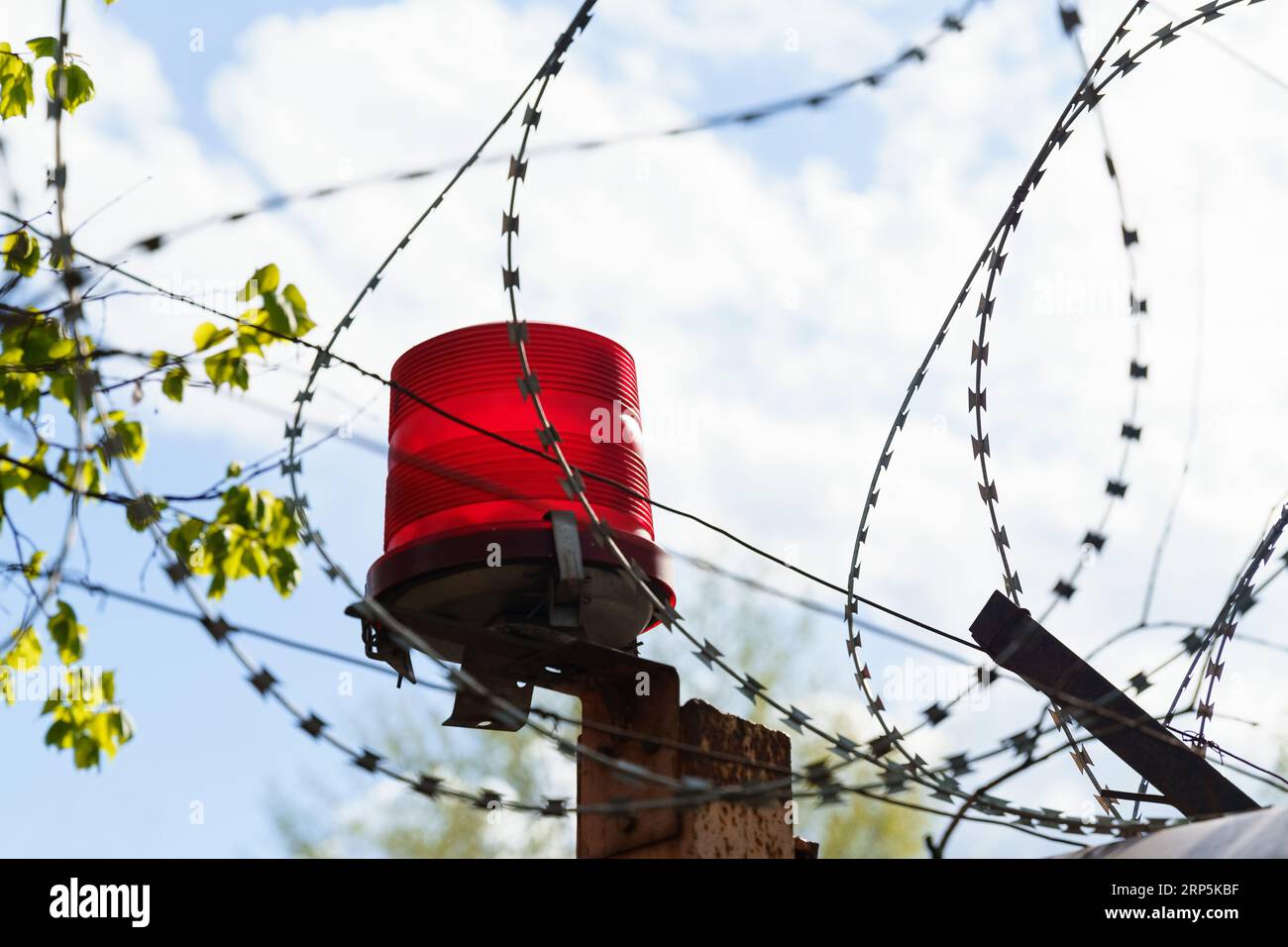 Protected area. A fence with barbed wire and a red flasher against a ...