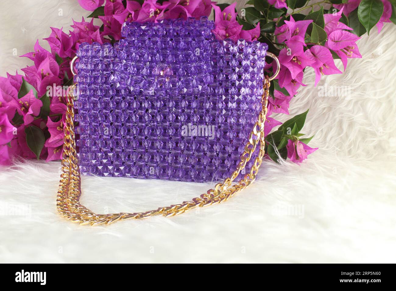 Handmade purple purse made with bright beads on white furry blanket ...
