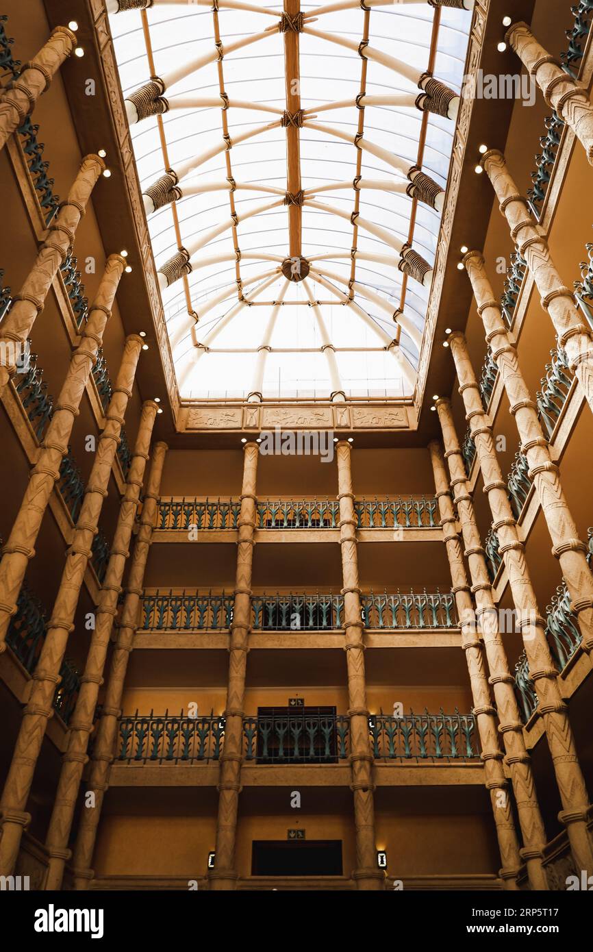 A towering structure with grand columns and a vast glass-covered roof ...