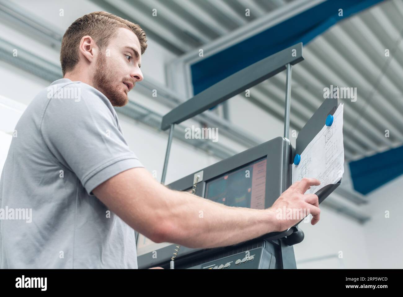Worker entering data on screen of a modern machine tool in factory ...