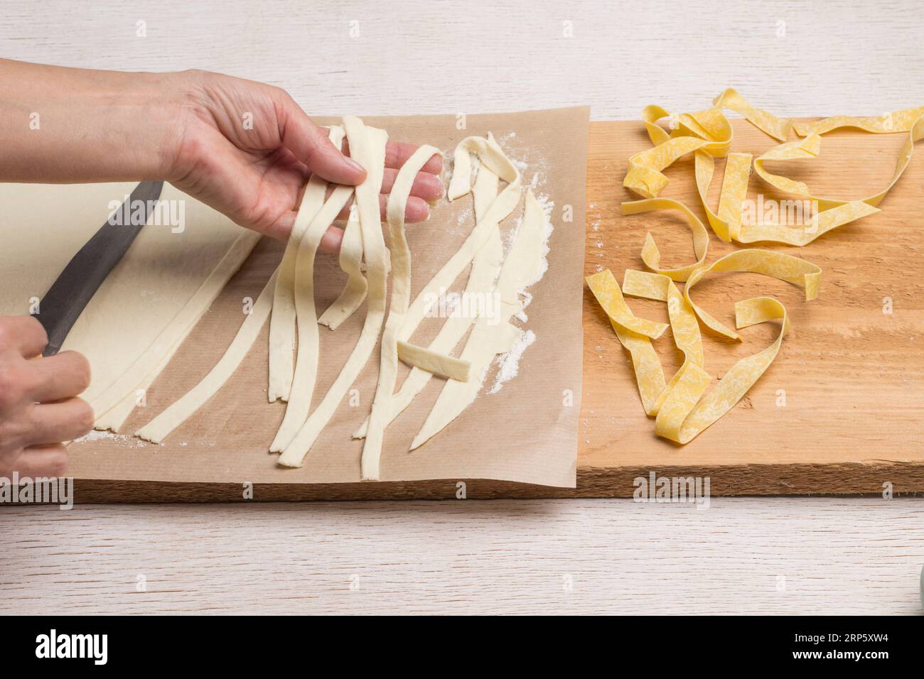 Hands make fresh pasta handmade. Rolled dough, sliced into strips ...