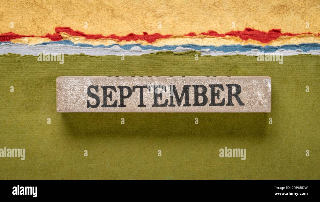 September text on grunge wooden block against handmade rag papers ...