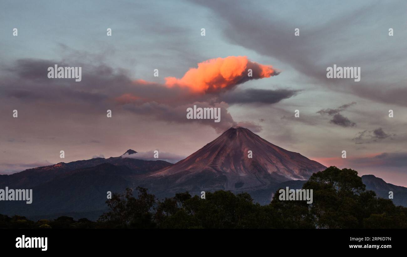 Colima's volcanoes at sunset. The iconic Volcano de Fuego gracefully ...