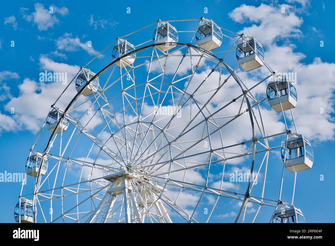 Modern ferris wheel in an amusement park against blue sky with clouds ...