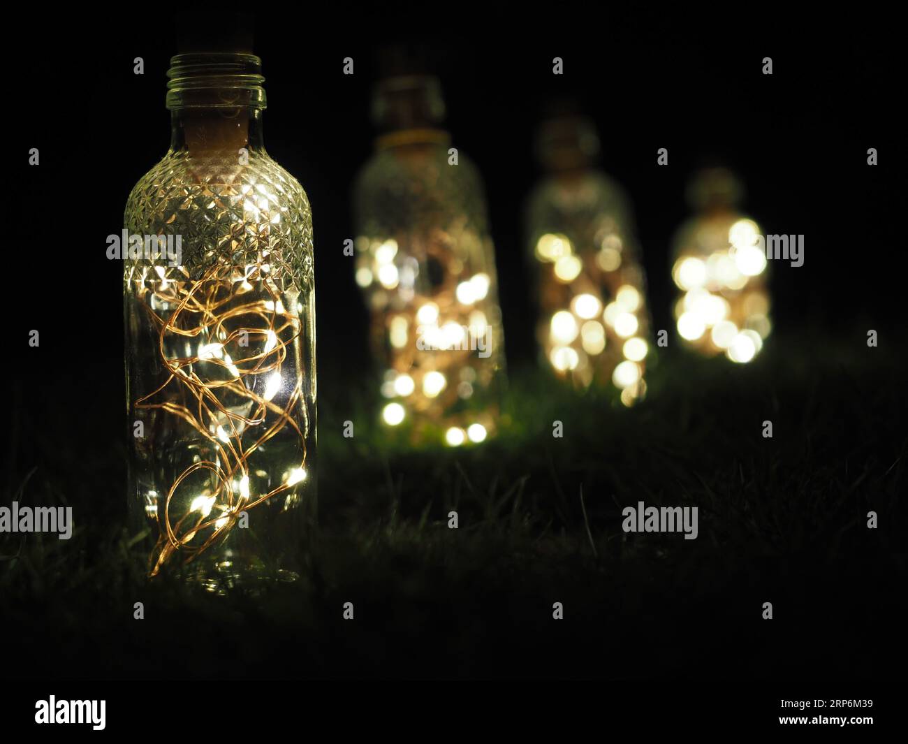 Glass bottle lights lined up on grass on a summer evening Stock Photo ...