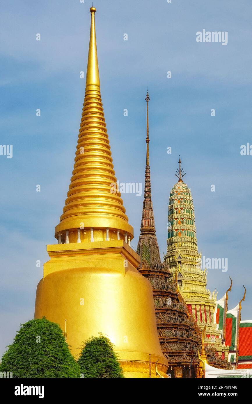 A temple in Thailand with golden spires. The temple has a large golden ...