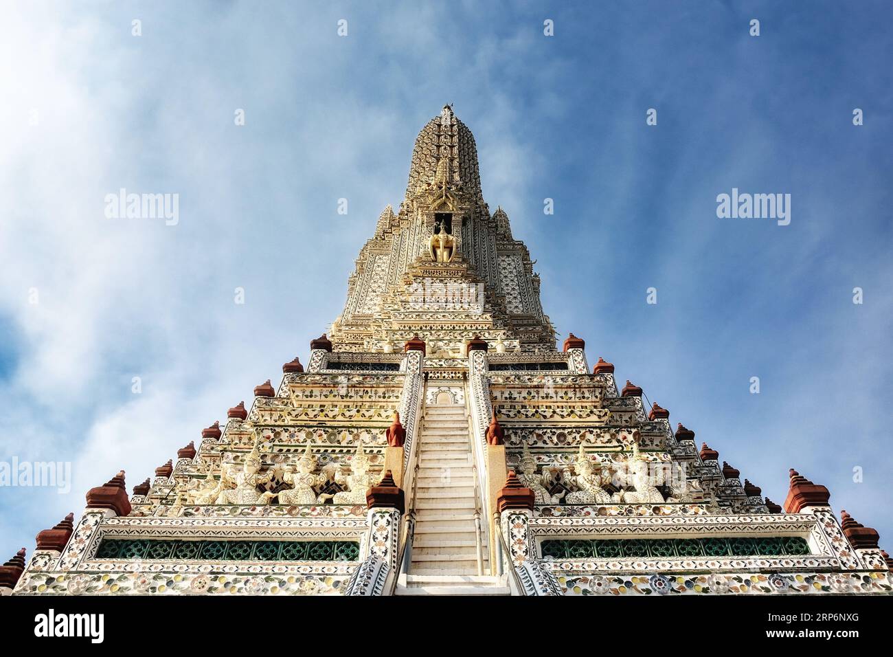 A temple in Thailand with a tall, ornate spire and a staircase leading ...