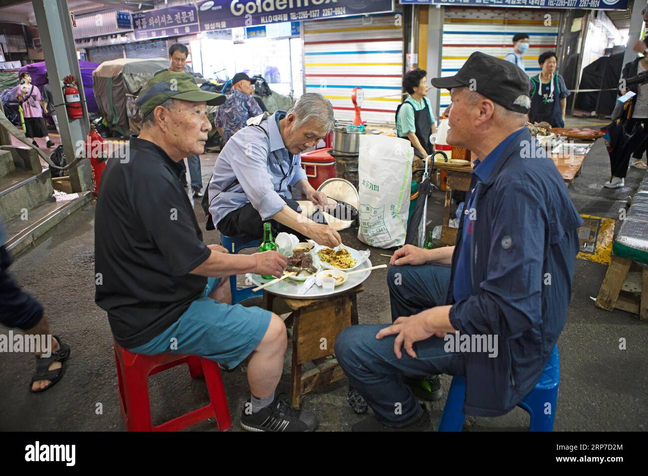 Old men sitting on plastic stools and eating at Gwangjang Market ...