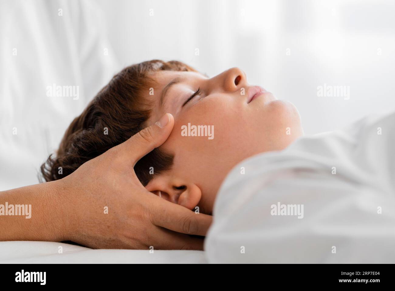 Female osteopathist treating child by massaging his head Stock Photo ...