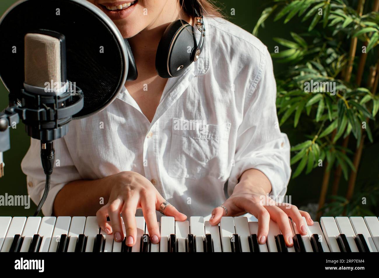 Smiley female musician playing piano keyboard indoors singing into ...