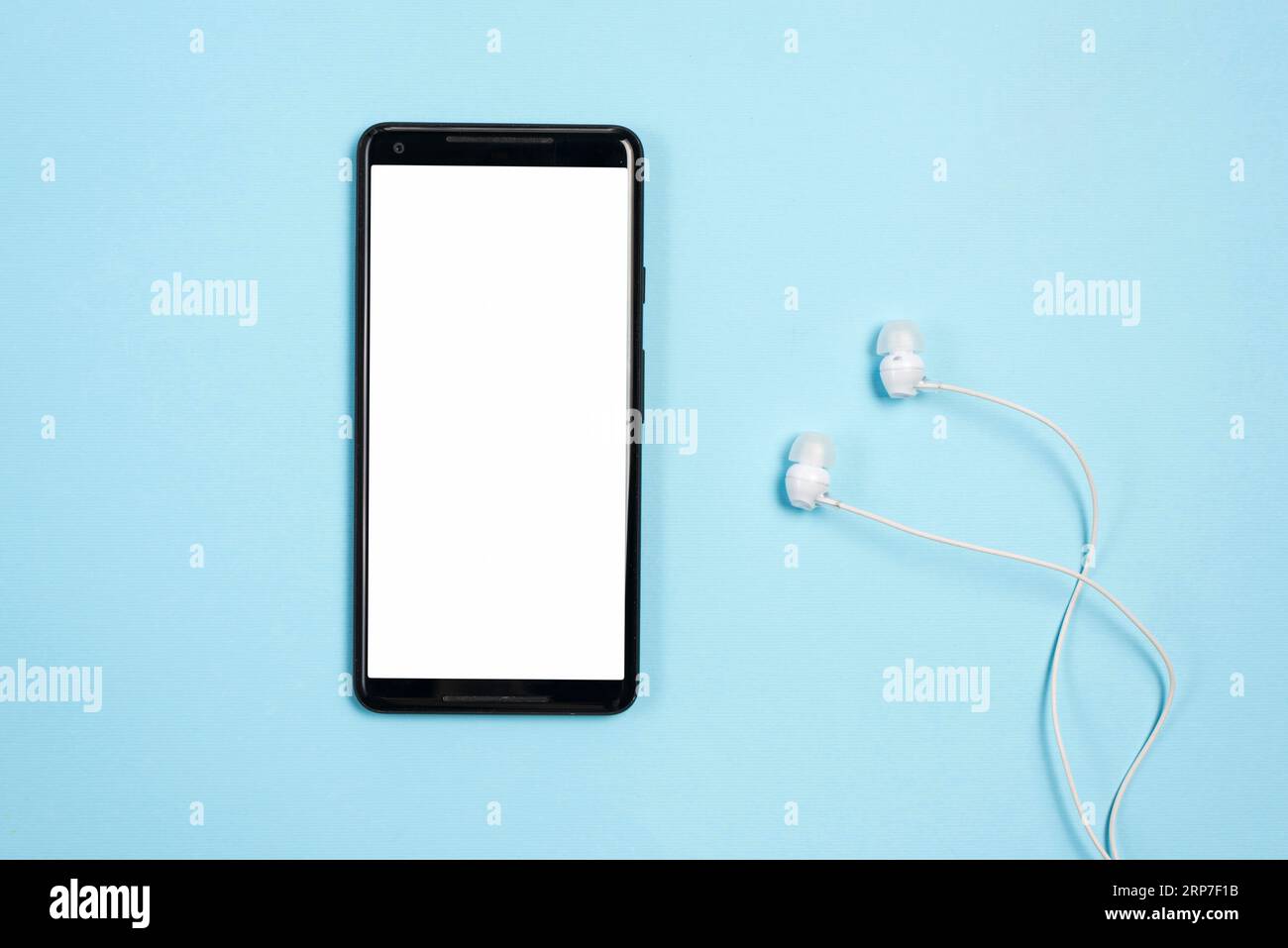 White blank screen display mobile phone with earphones against blue ...
