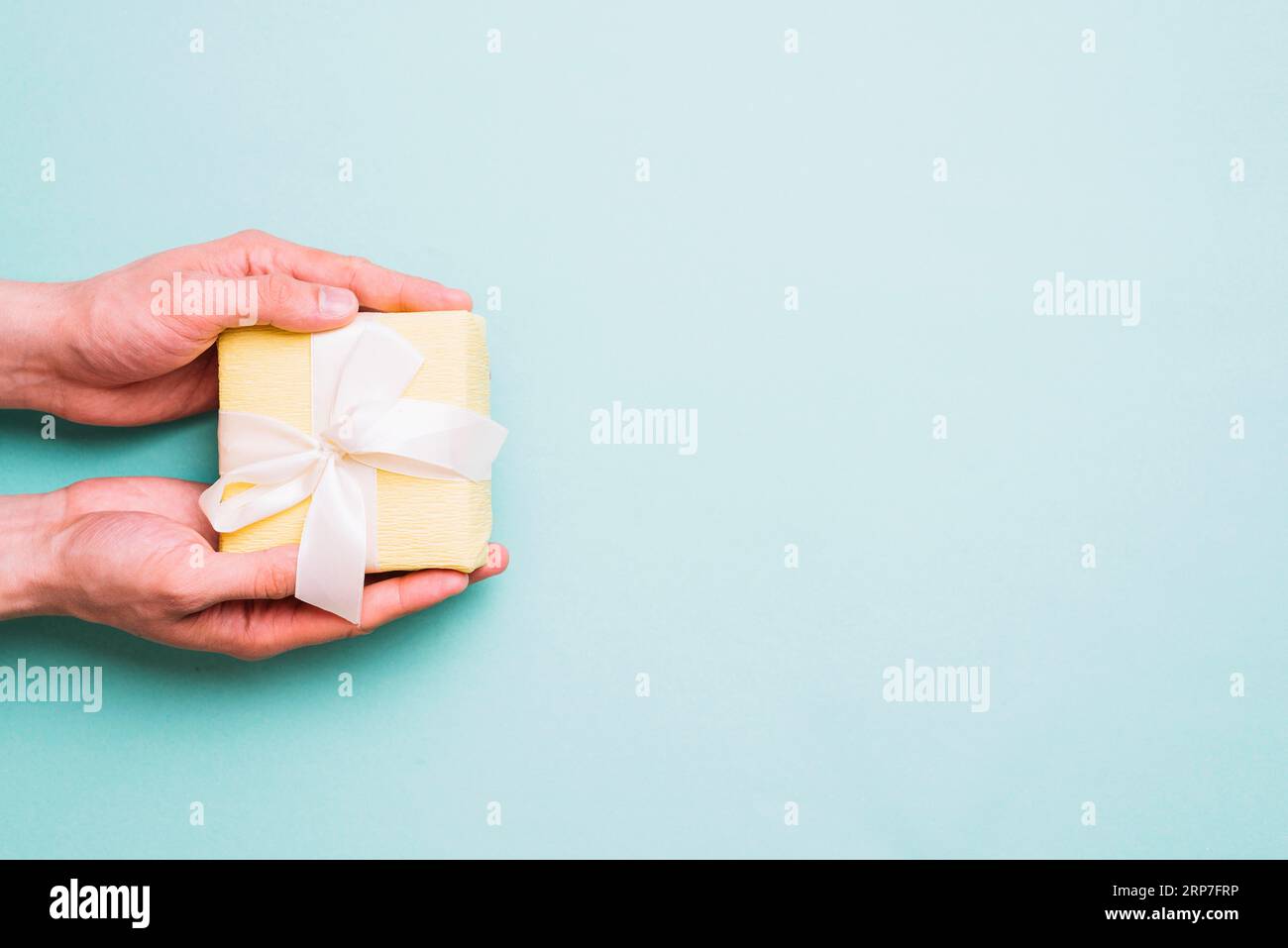 Person s hand holding small gift box against blue background Stock ...