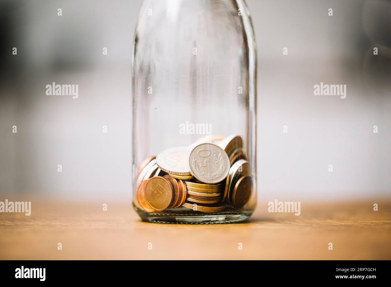 Coins glass bottle wooden surface Stock Photo - Alamy