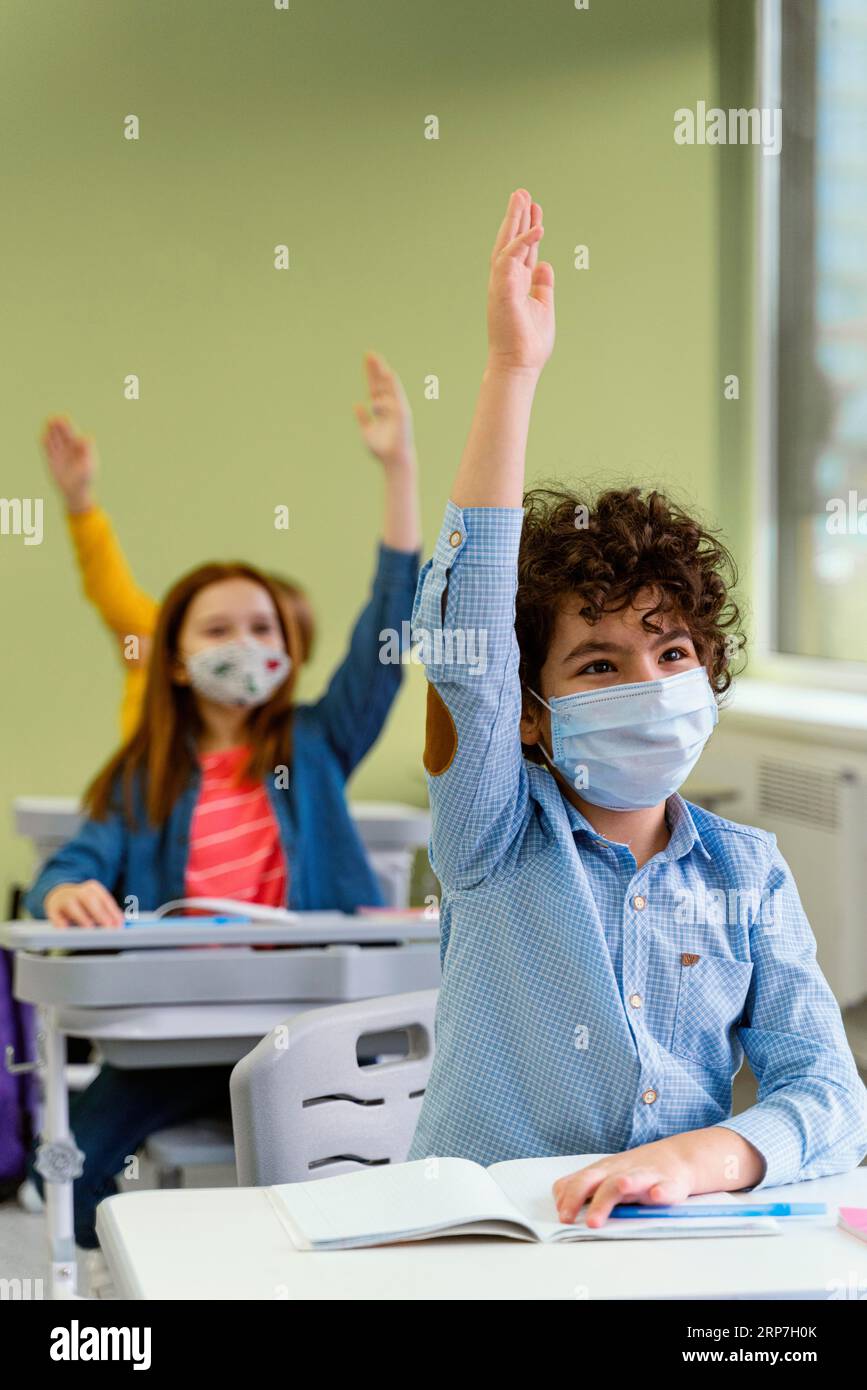 Front view children raising their hands class Stock Photo - Alamy