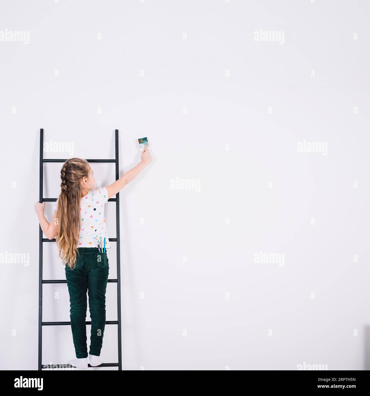 Little girl ladder painting wall Stock Photo - Alamy