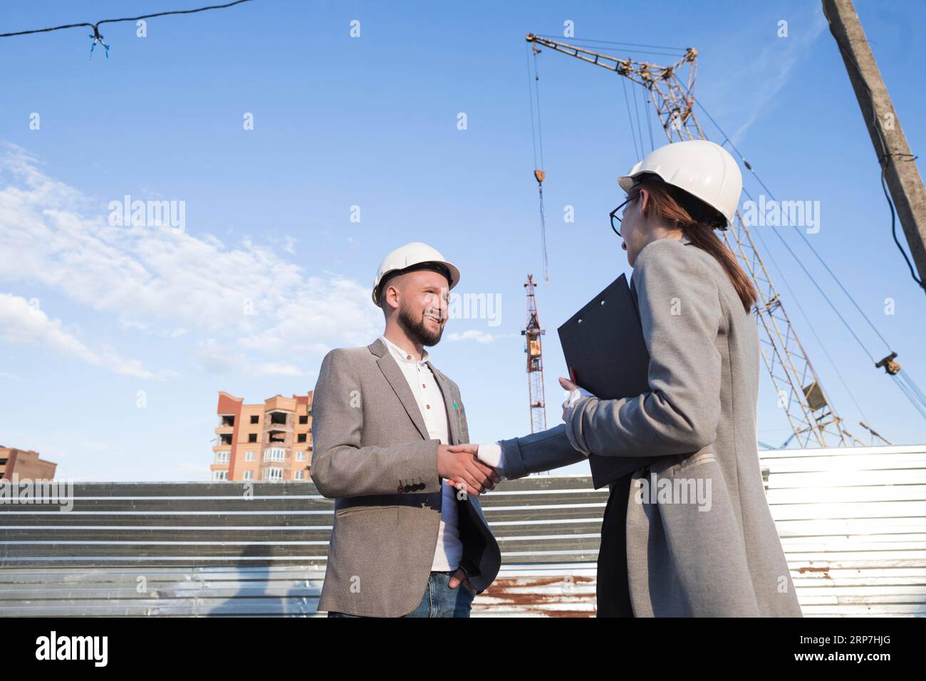 Smiling engineers shaking hands construction site architectural project ...