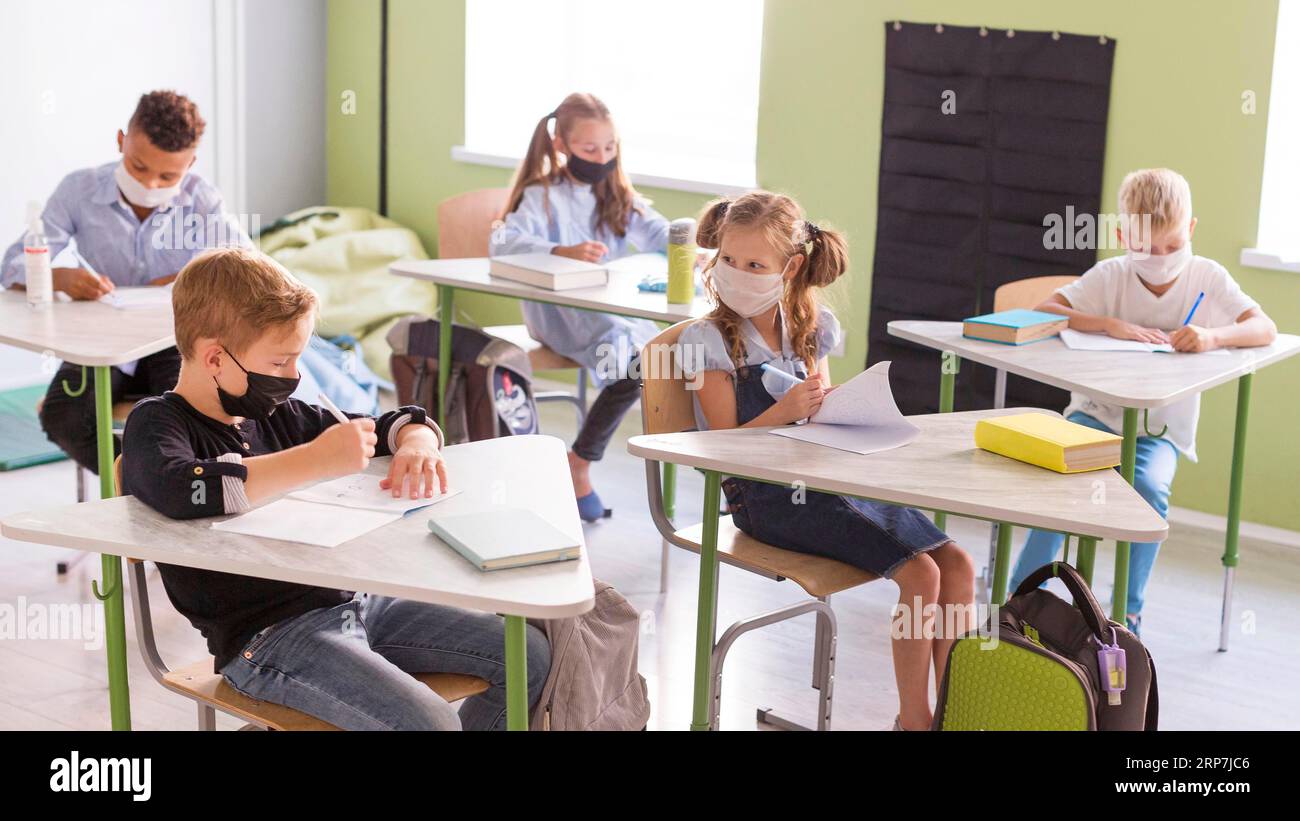 Kids protecting themselves with face masks class Stock Photo - Alamy