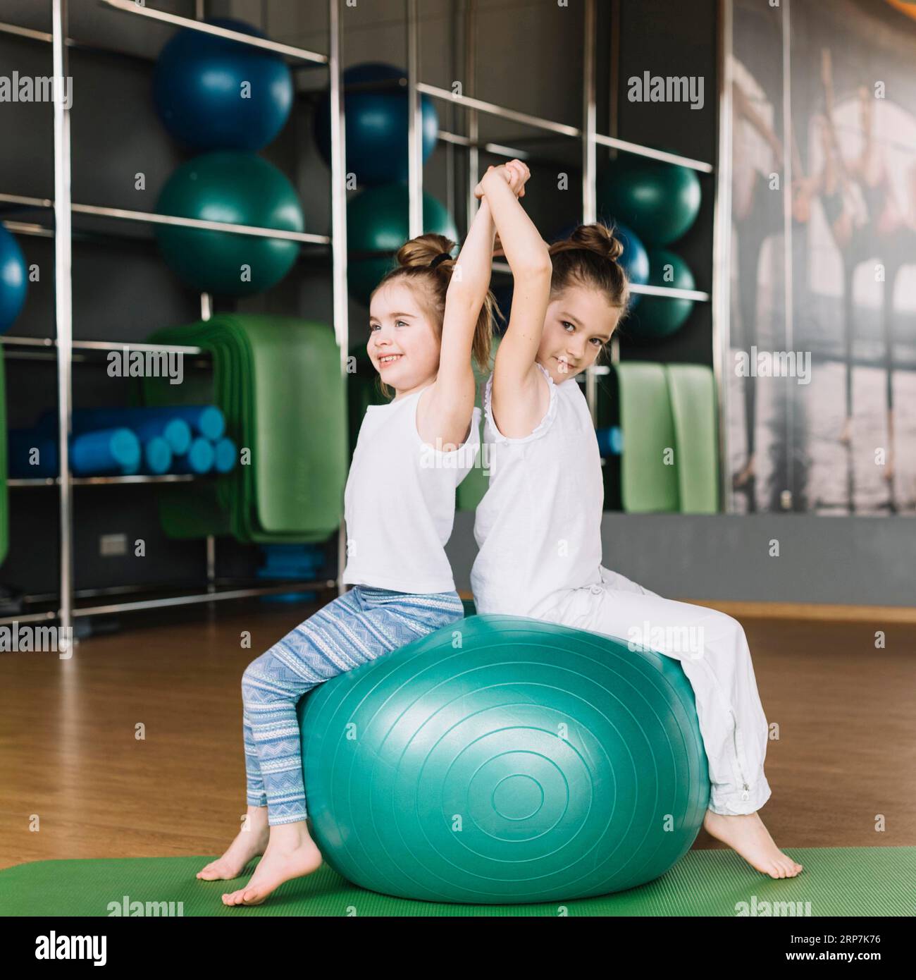 Two little girl sitting back back exercising ball together Stock Photo ...