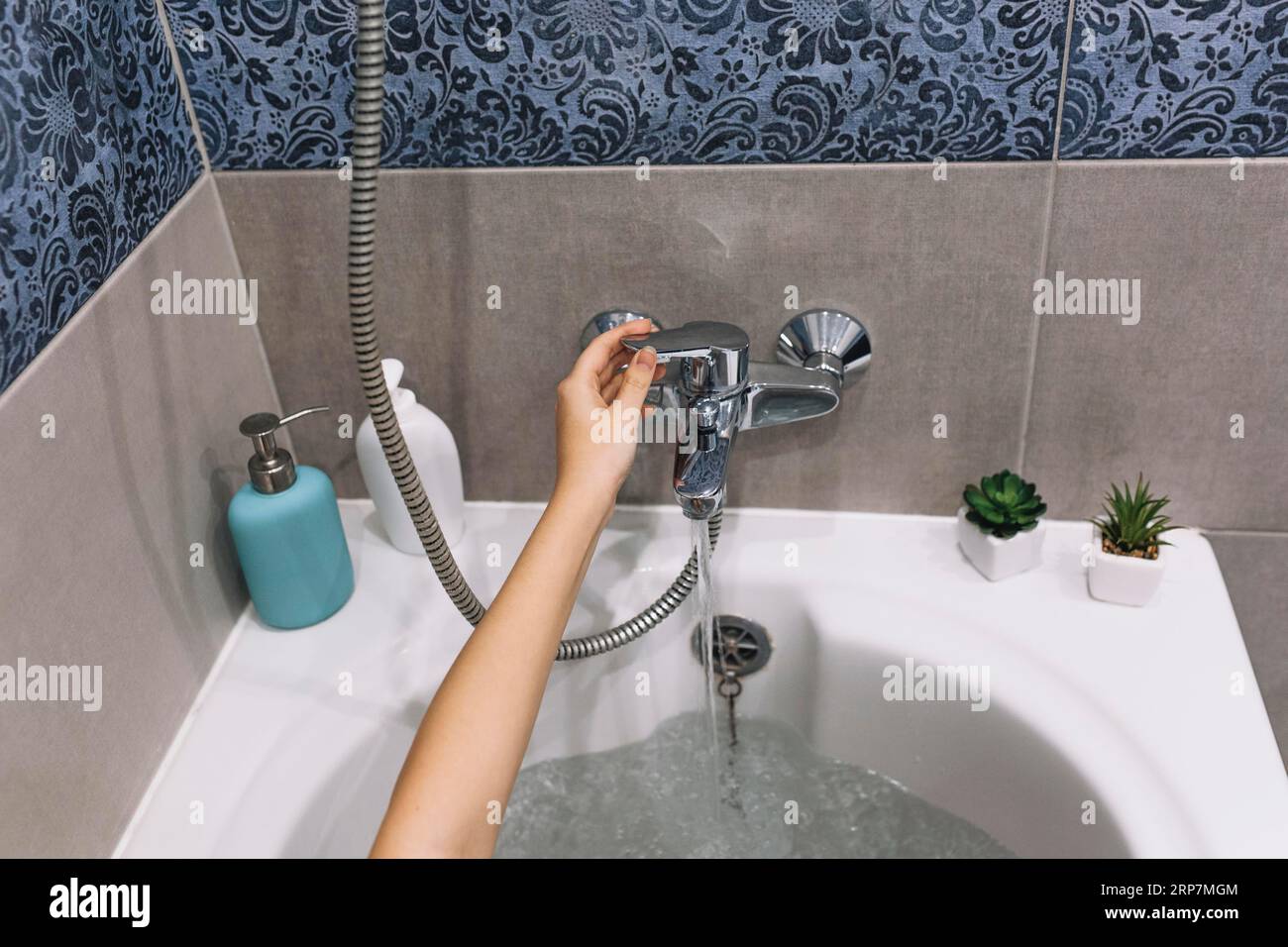 Crop hand touching bath tap Stock Photo - Alamy