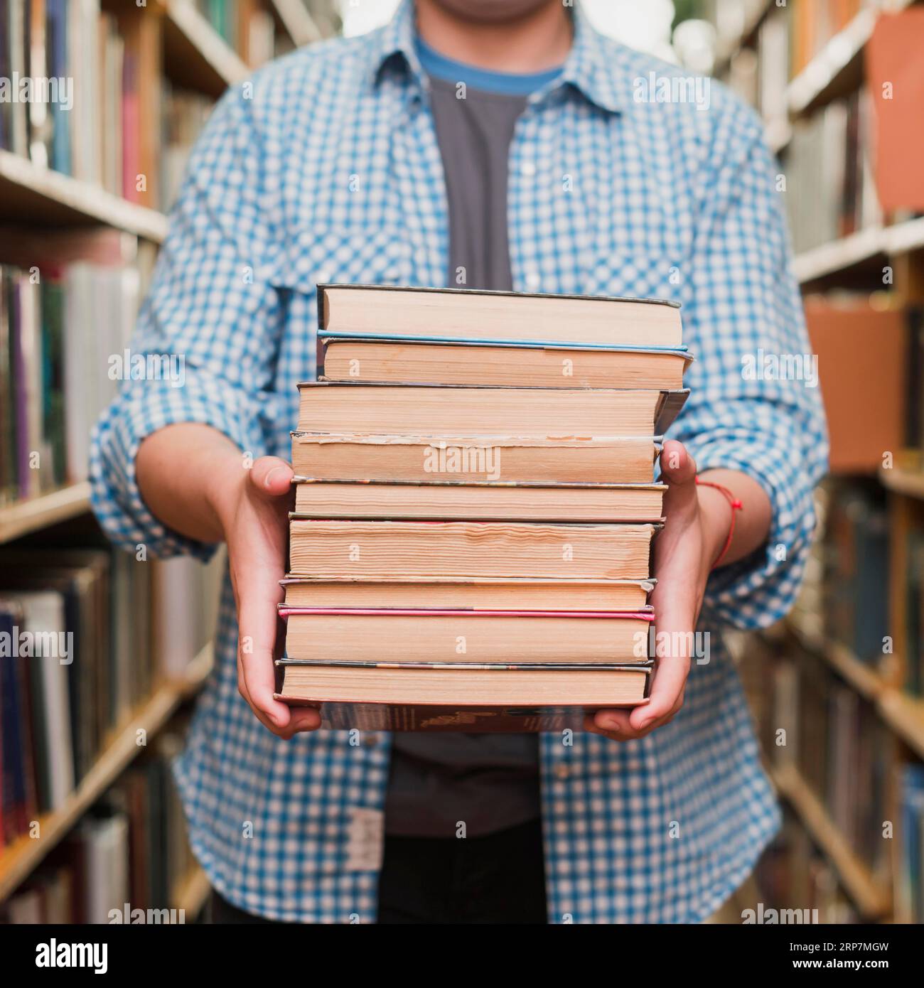 Crop teenager showing pile books Stock Photo - Alamy