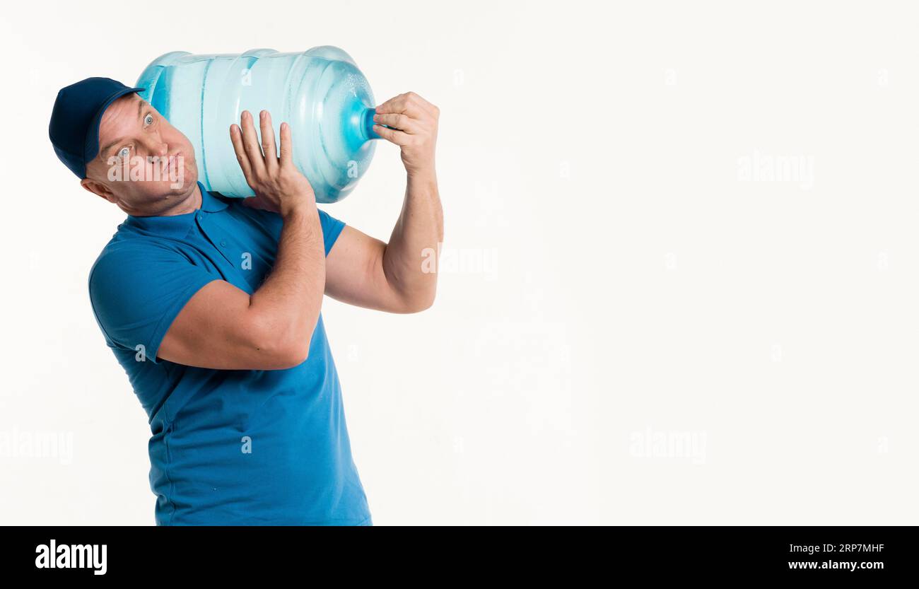 Delivery man carrying heavy water bottle Stock Photo - Alamy