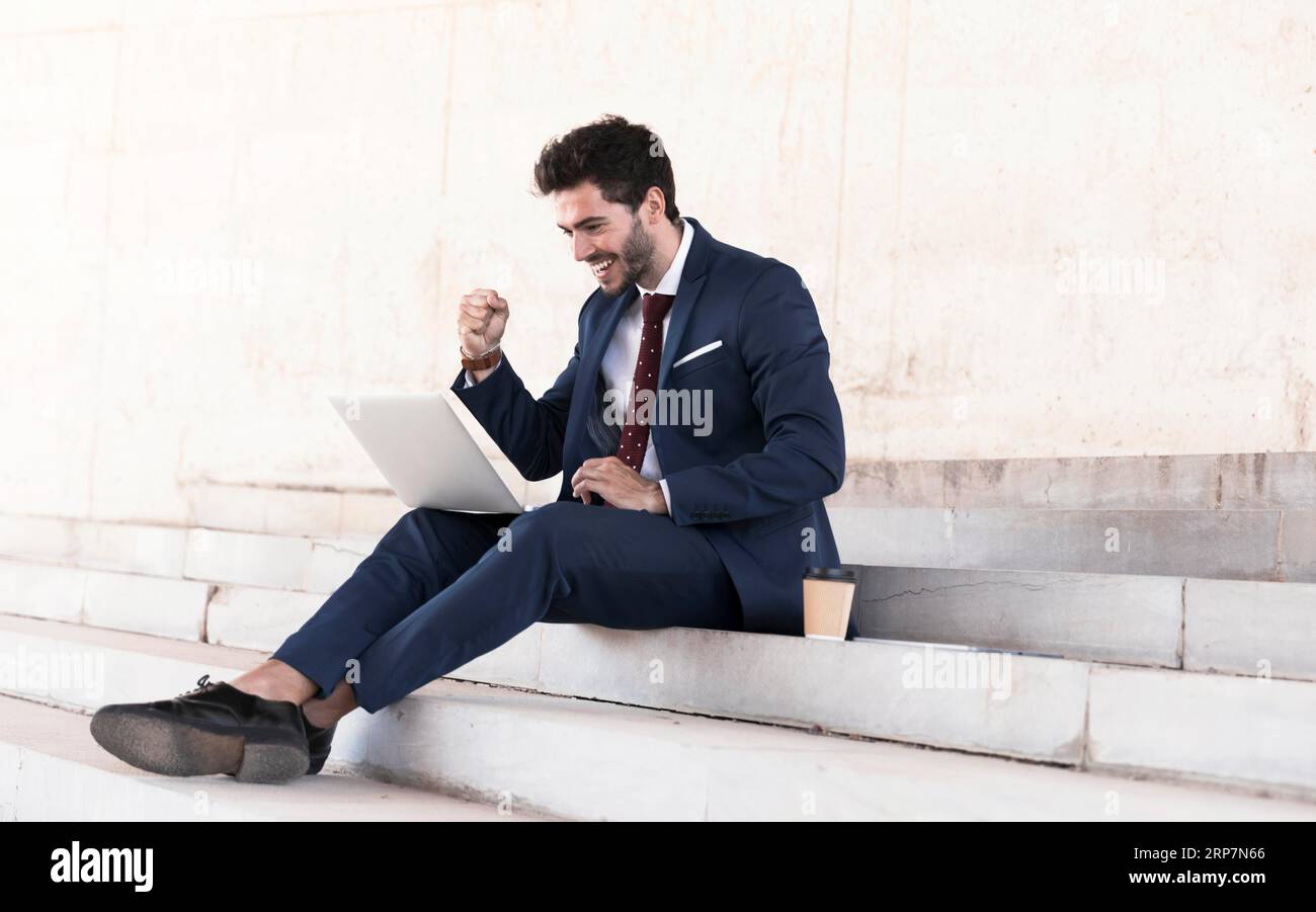Full shot sitting man expressing victory Stock Photo - Alamy