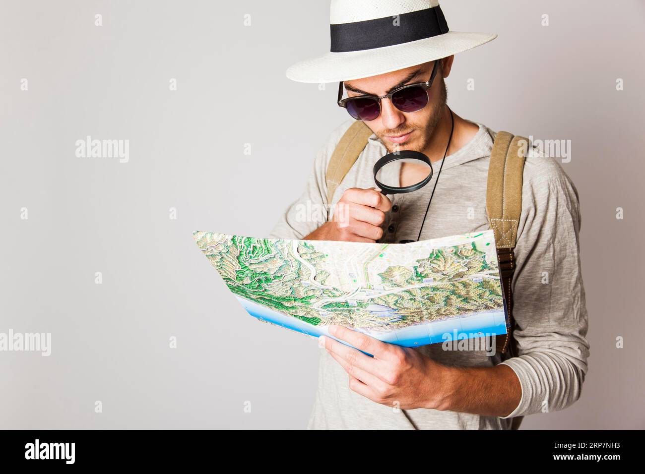 Hipster man with map magnifying glass Stock Photo - Alamy