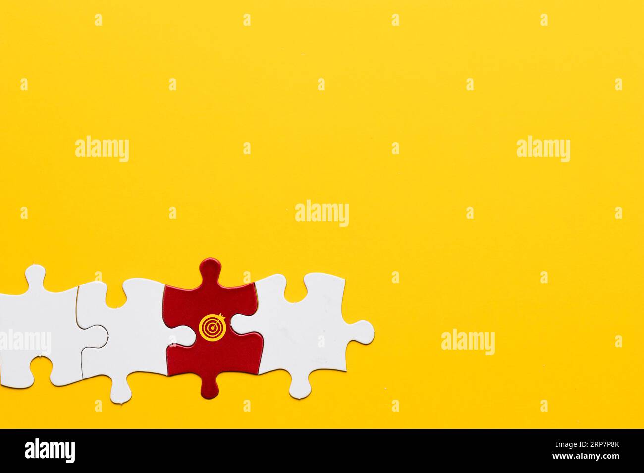 Red jigsaw puzzle piece with dartboard symbol arranged with white piece ...