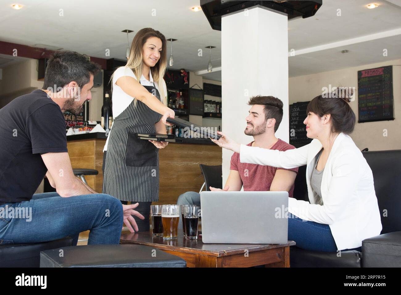 Waitress presenting menu female customer with friends bar Stock Photo ...