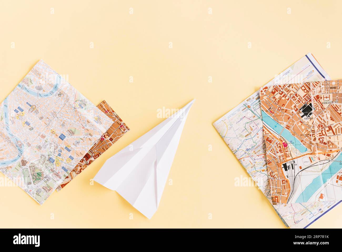 Variety maps with white paper airplane beige background Stock Photo - Alamy