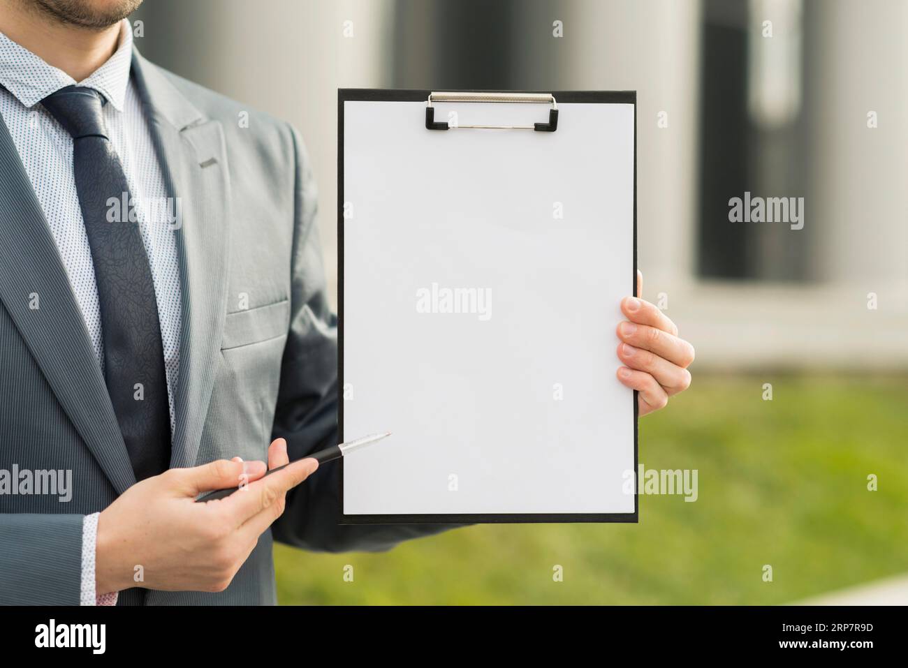 Businessman presenting clipboard Stock Photo - Alamy