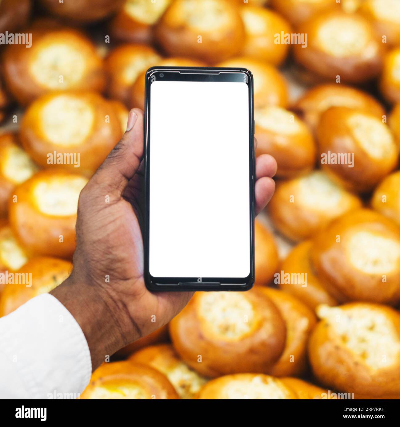 Crop hand with smartphone pastry background Stock Photo - Alamy