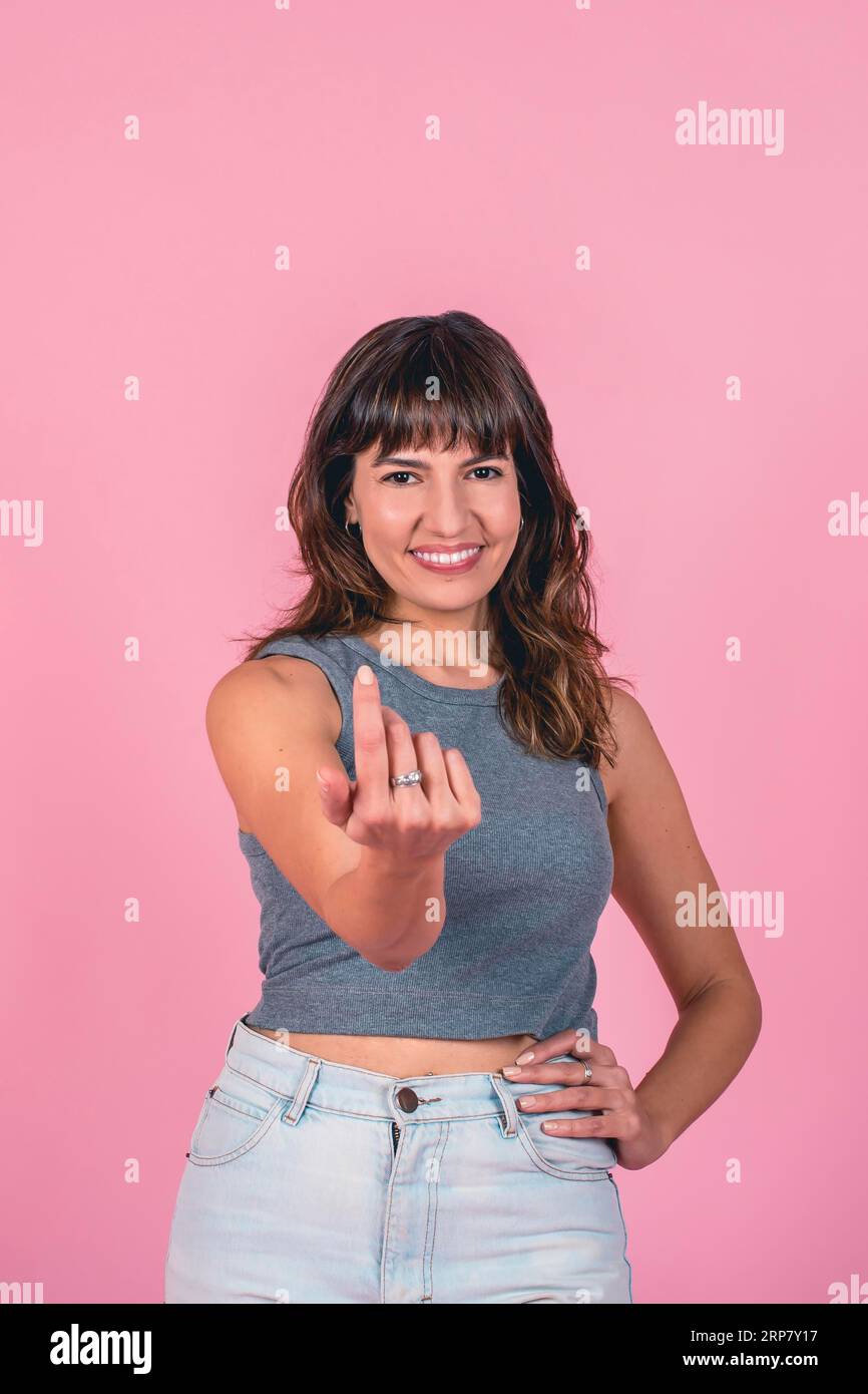 Studio portrait of a woman calling with one finger, making beckoning ...