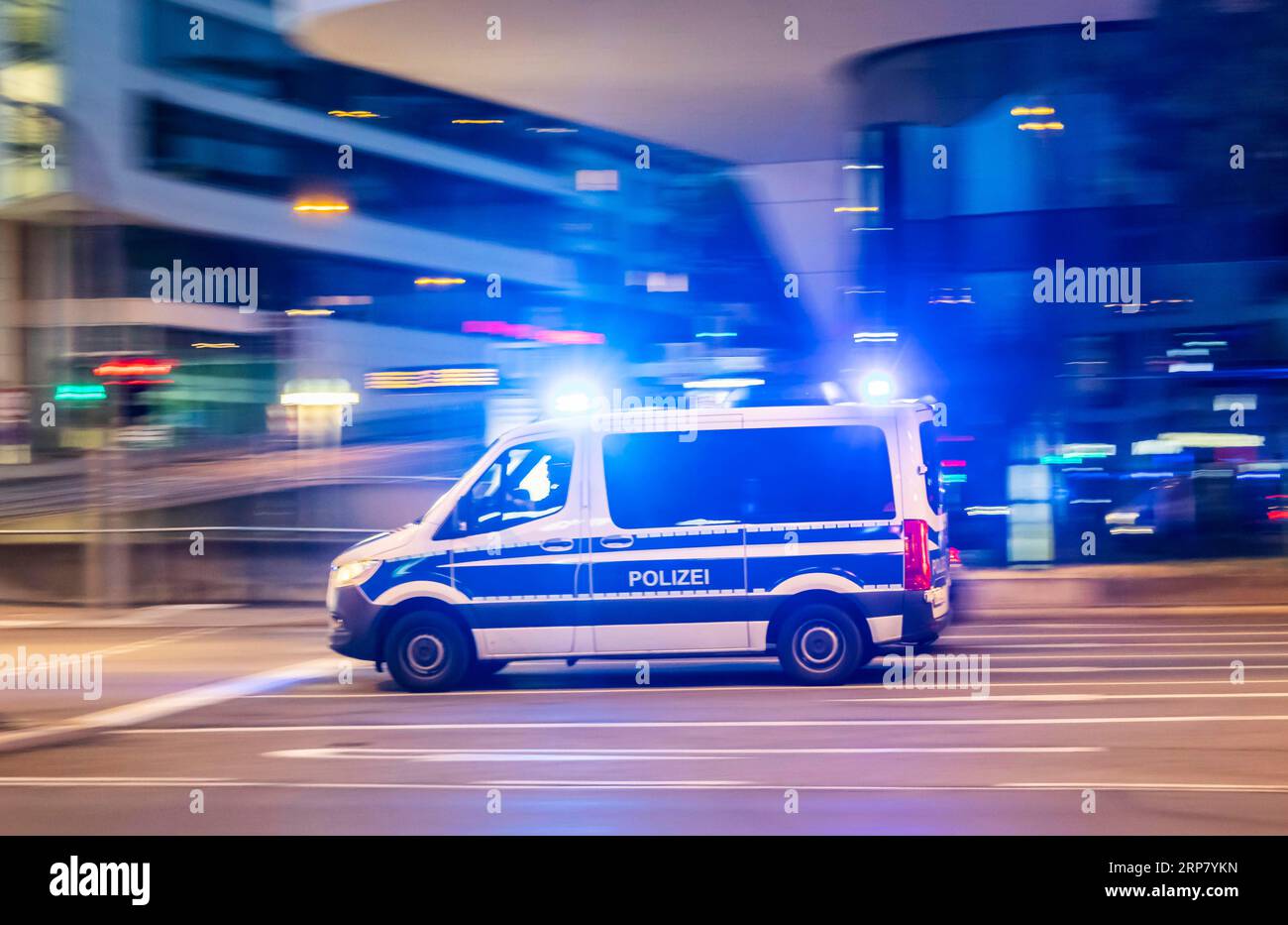 Police vehicle with blue lights at night in front of urban surroundings ...