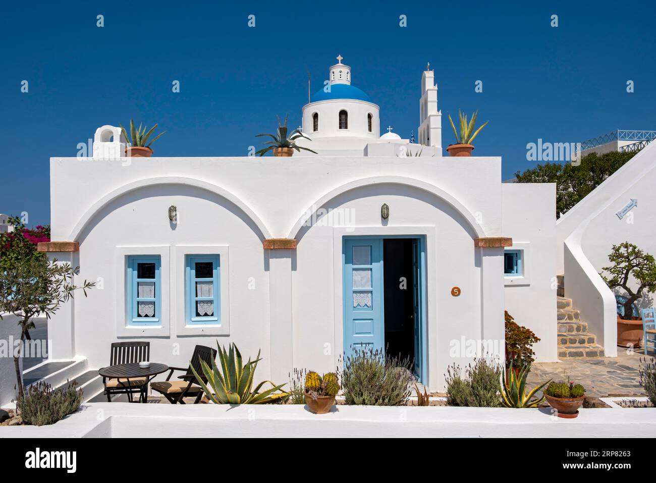 White house with blue door and church of Panagia Platsani, Ia, Oia ...