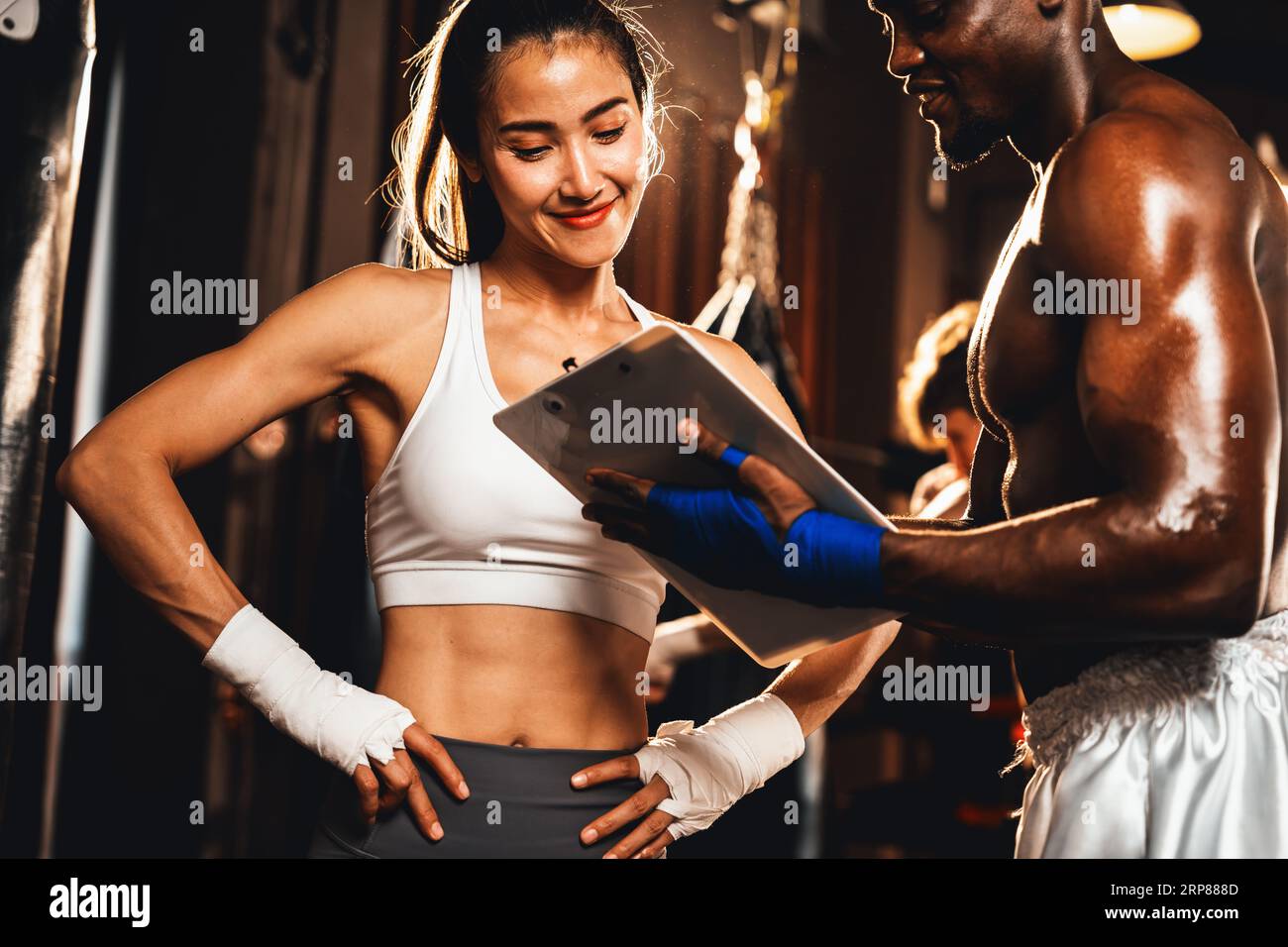 Asian female Muay Thai boxer and her personal boxing trainer discussing ...