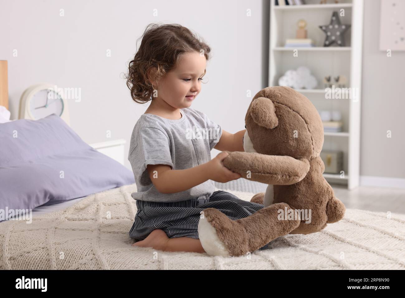 Cute little girl playing with teddy bear on bed at home Stock Photo - Alamy