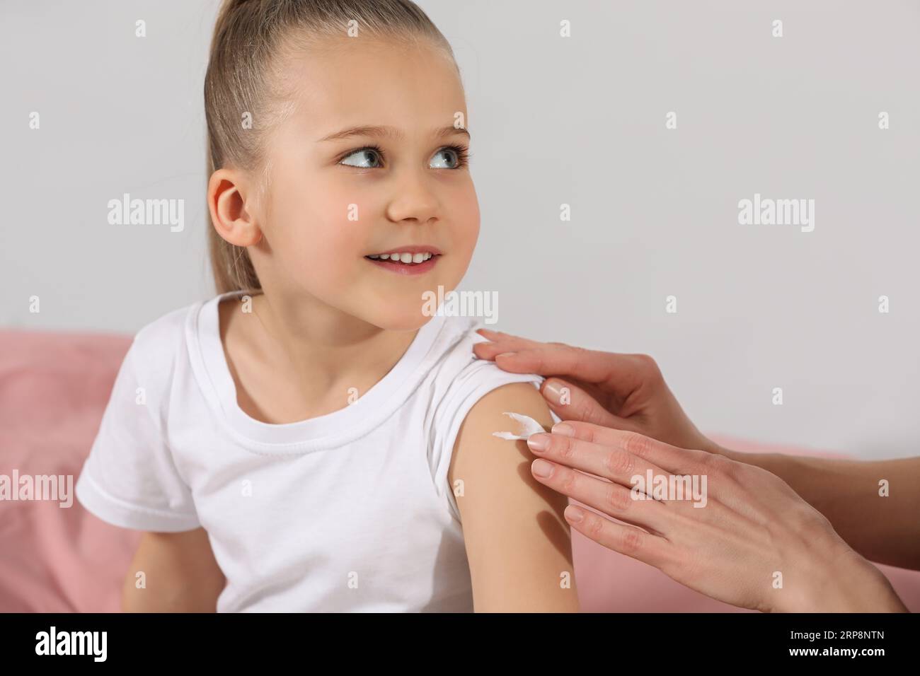 Mother applying ointment onto her daughter's arm on bed Stock Photo - Alamy