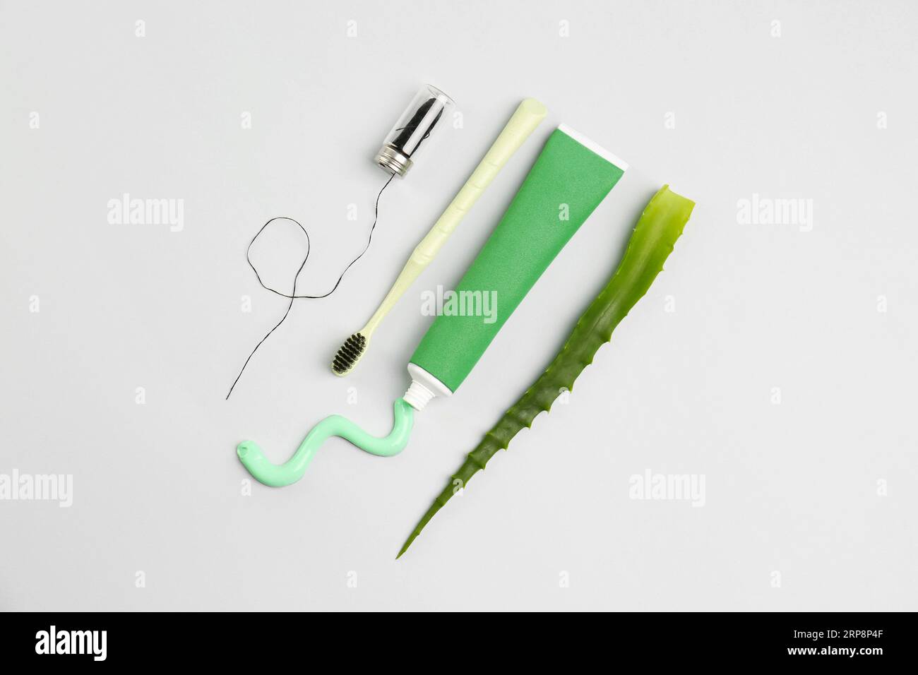 Tube of toothpaste, toothbrush, dental floss and fresh aloe on light ...