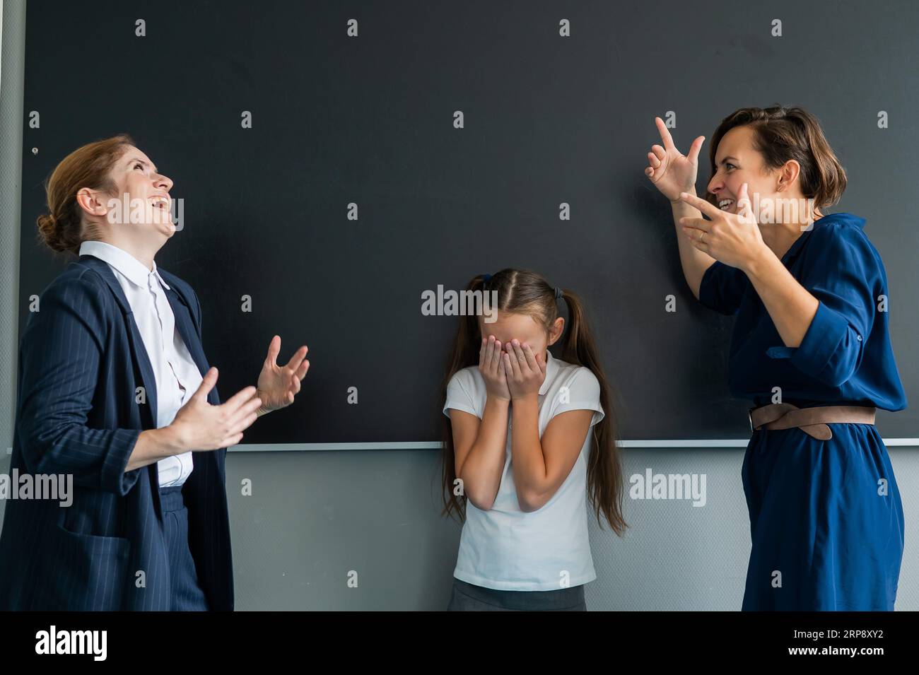 A female teacher and a student's mother yell at each other at the blackboard. The schoolgirl is ...