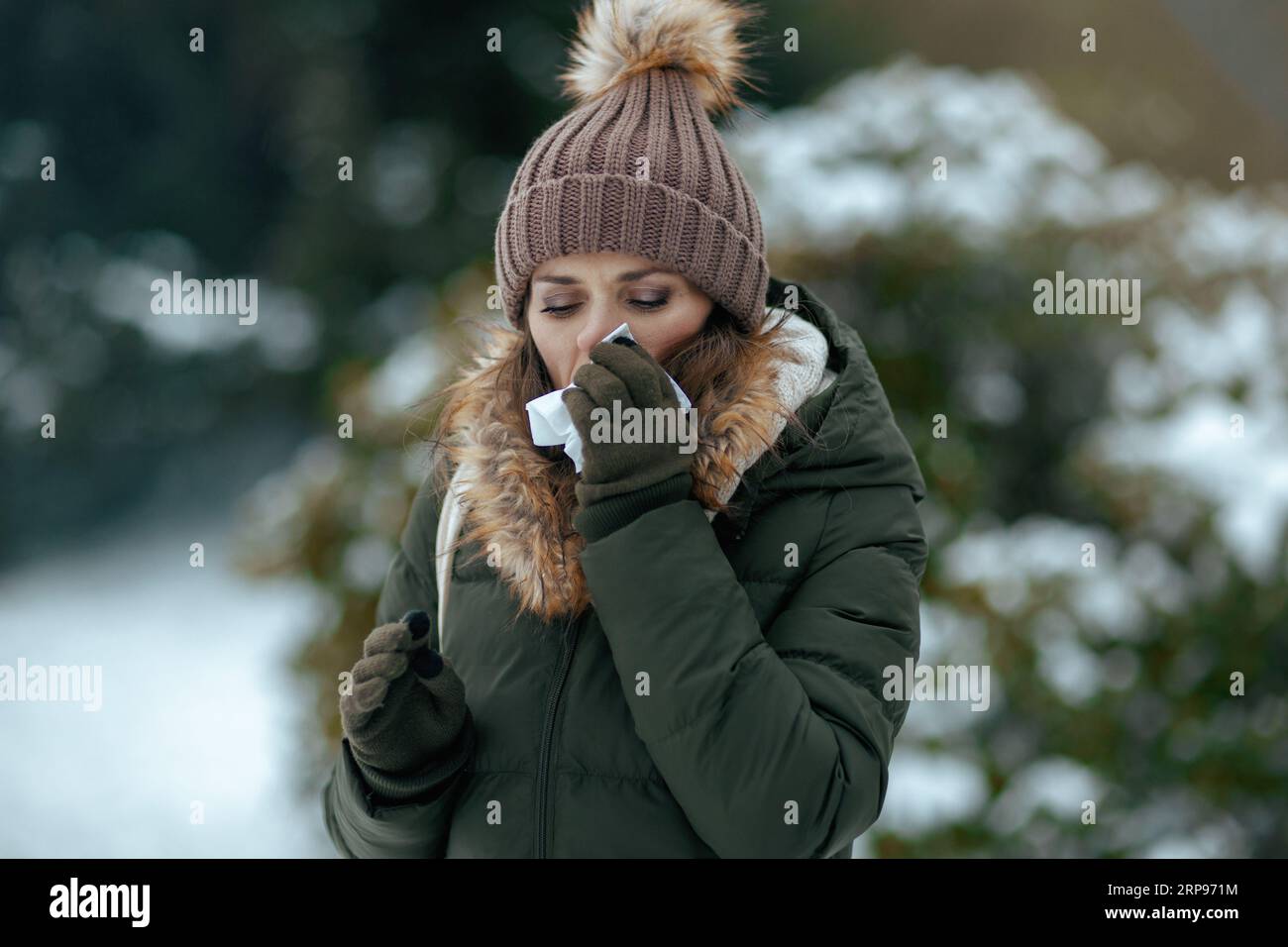 sad modern 40 years old woman in green coat and brown hat outdoors in ...