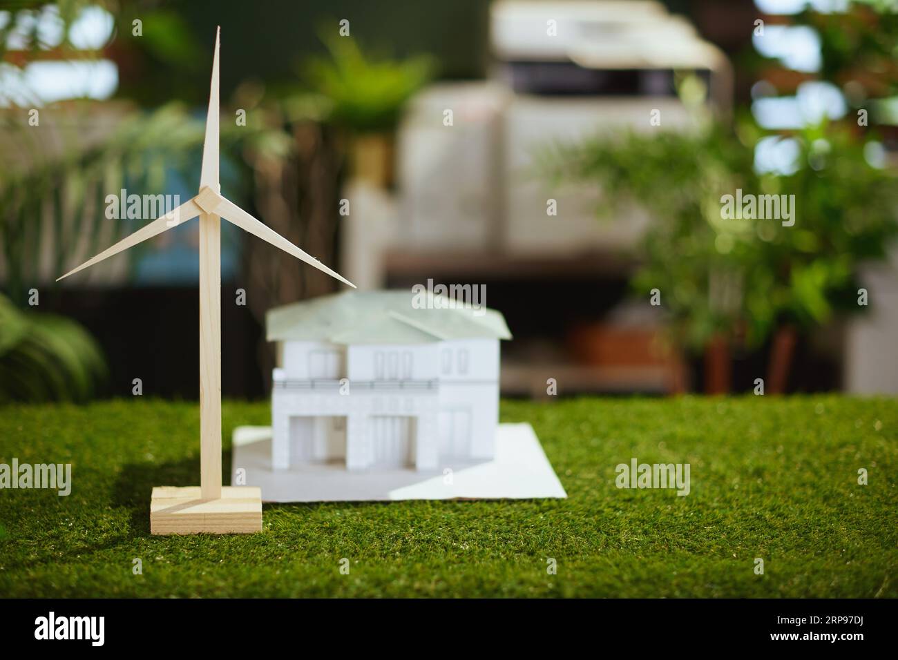 Time to go eco. grass table in modern green office with paper house and ...